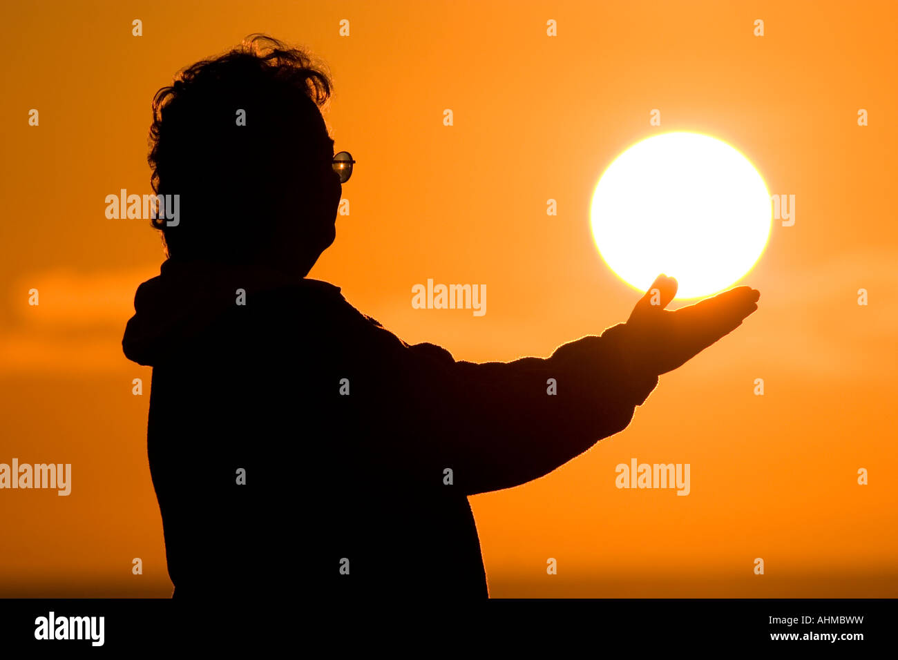 Middle aged Woman holding the morning Sun in her hands Stock Photo - Alamy