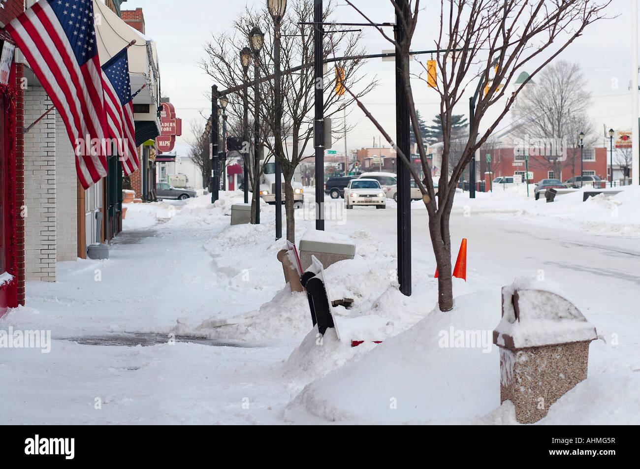 Snow covered sidewalks and roads in a small town with American flags ...