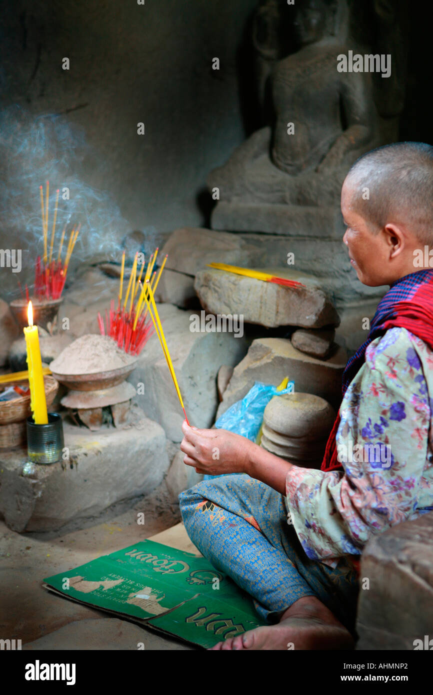 Khmer woman at prayer at a Buddhist shine, Ta Prohm, Siem Reap ...
