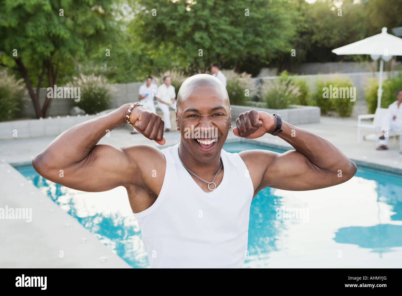 Man flexing his muscles by swimming pool Stock Photo - Alamy