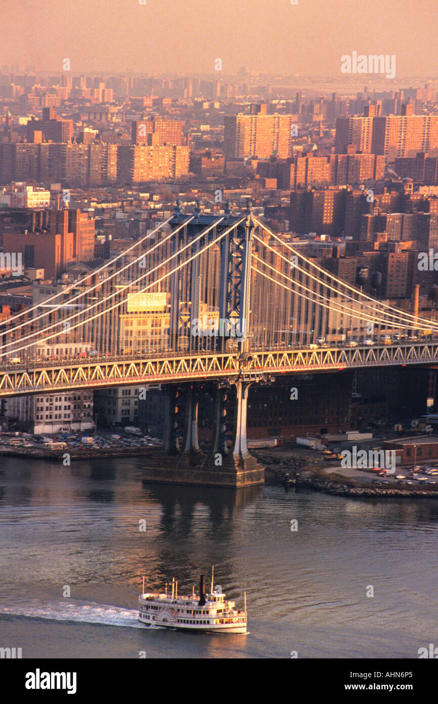 New York City Manhattan Bridge at dusk. Riverboat on the East River in ...