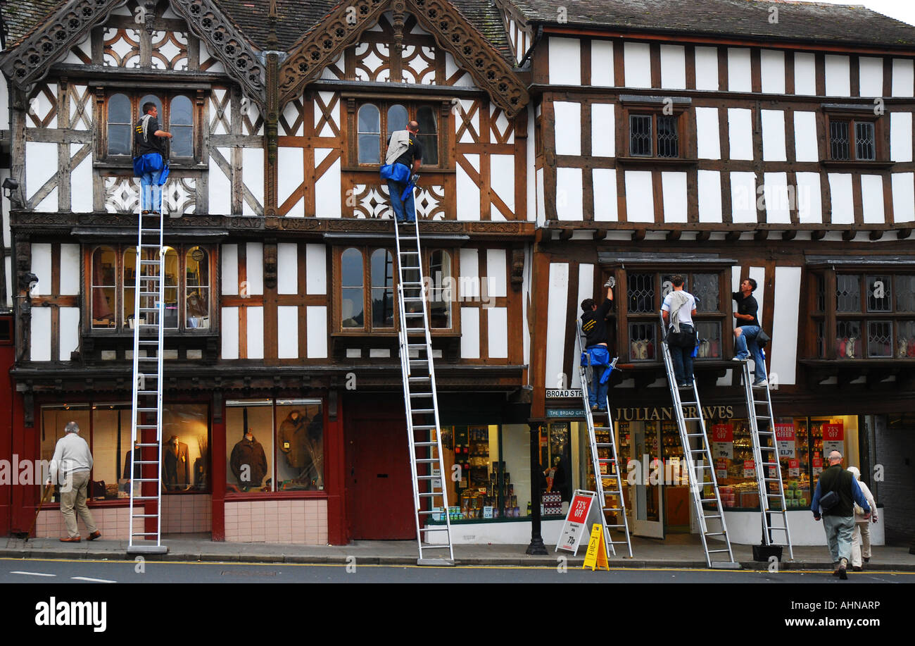 A team of window cleaners cleaning windows on black and white Tudor ...