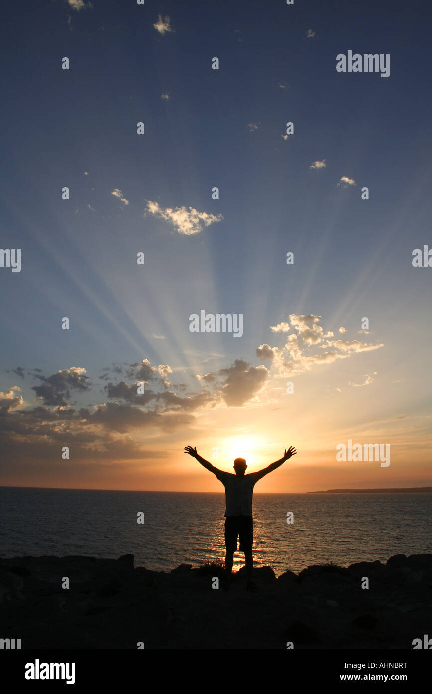 Man with arms aloft and outstretched with sunset in background. Taken ...