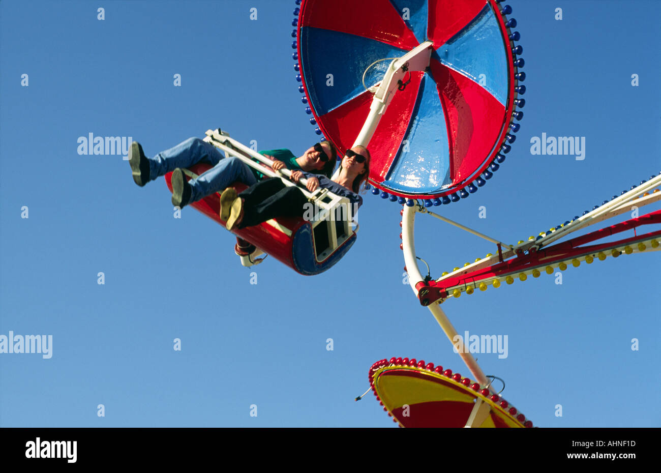 Two young women girls laughing enjoying carousel funfair ride in summer ...