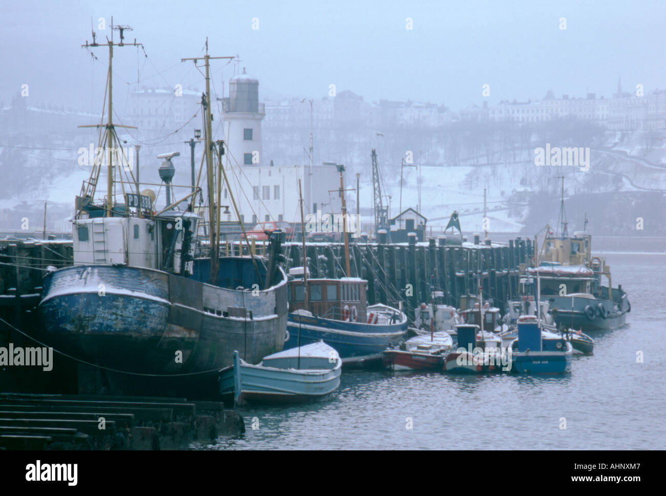 scarborough winter snow on fishing boats, with lighthouse beyond ...