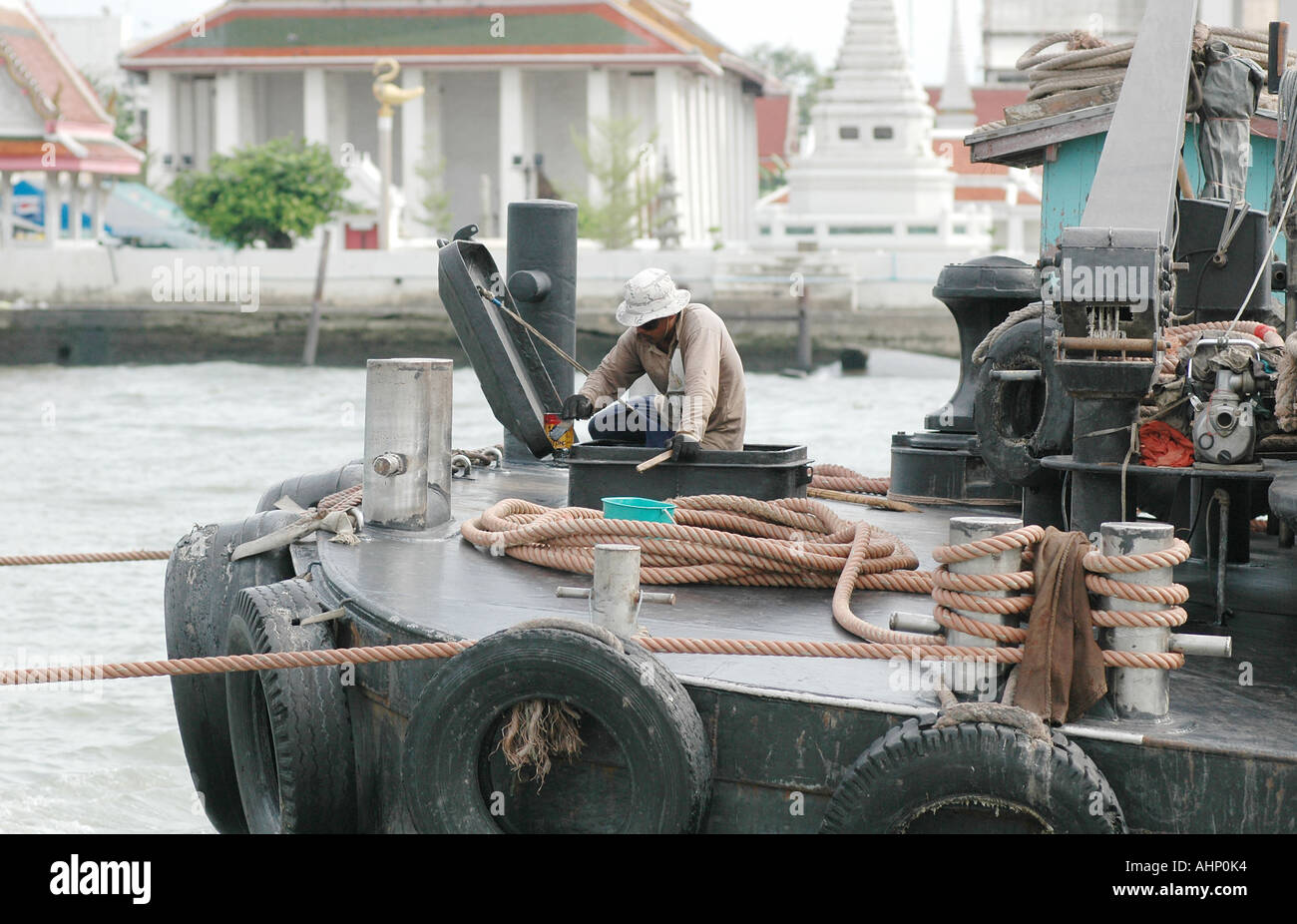 Man working on a barge along the Chao Phraya river in Bangkok Thailand ...