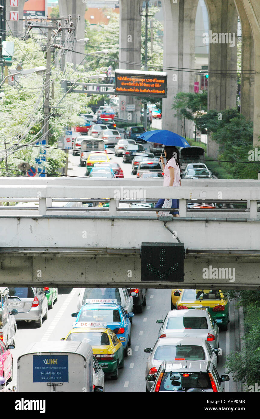 A lady shelters from the sunshine as she uses a walkway over Sukumvit ...