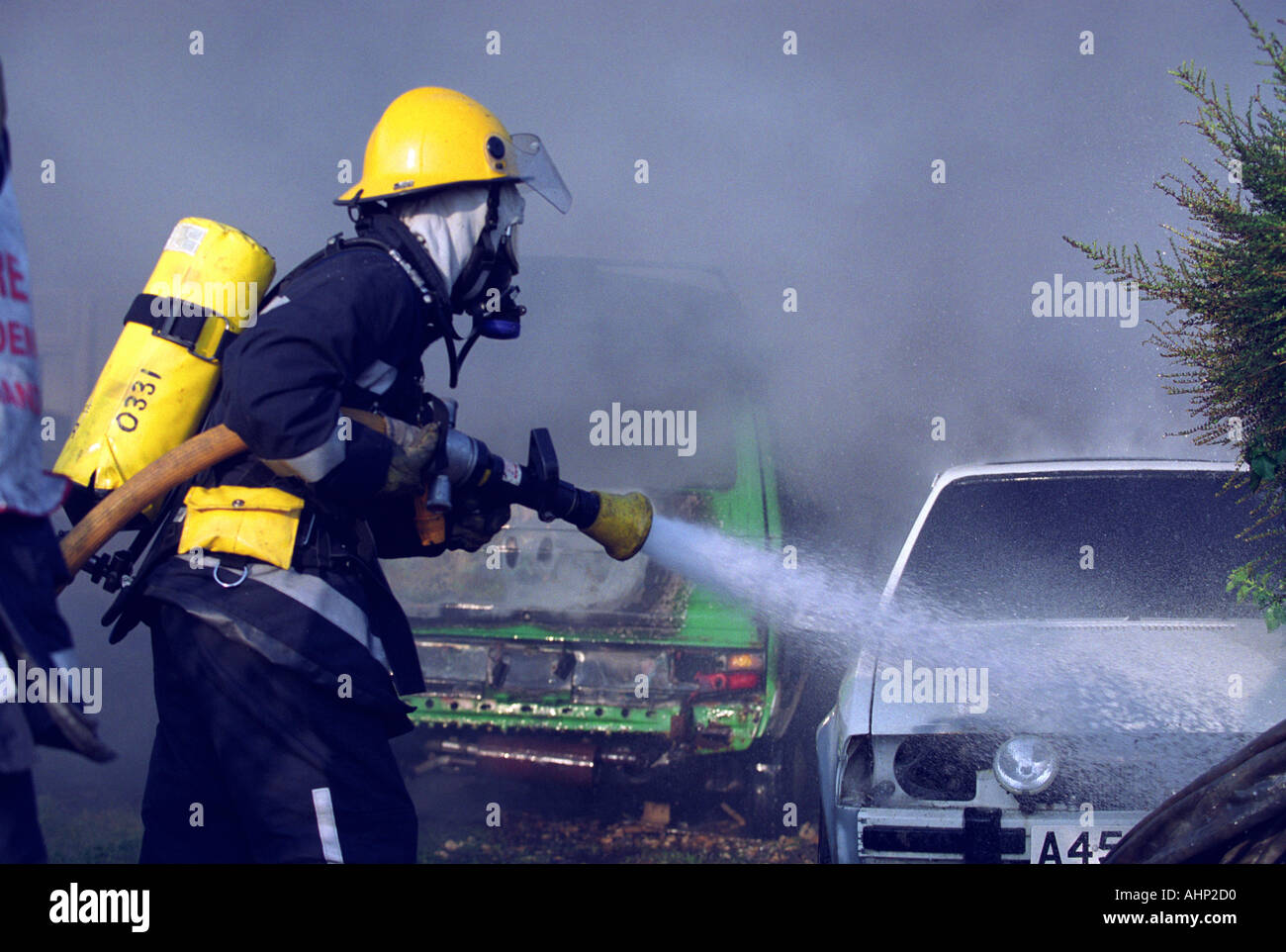 Firefighter using a hose reel jet to put out a car fire, Britain UK ...