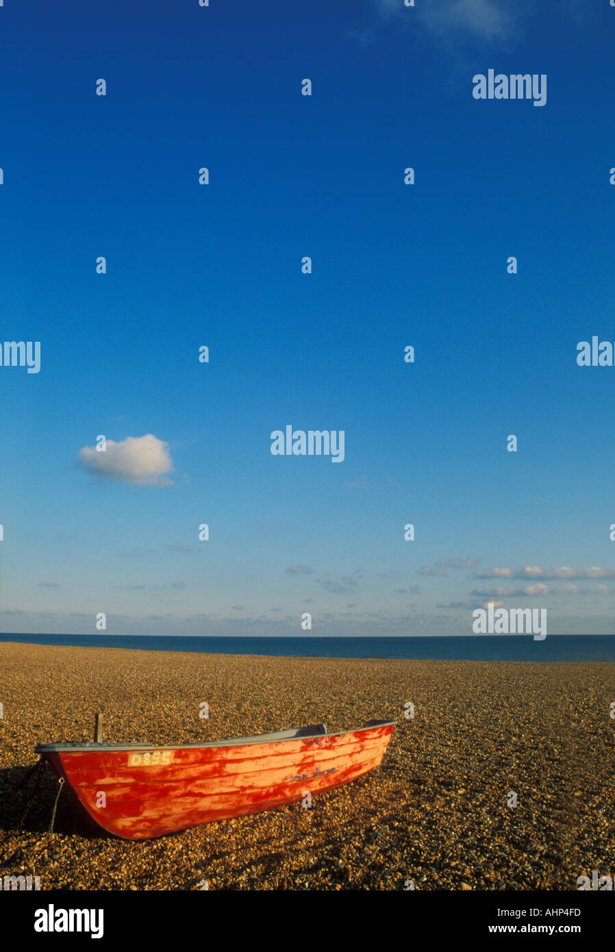 Single red rowing boat on the shingle of Brighton beach East Sussex ...