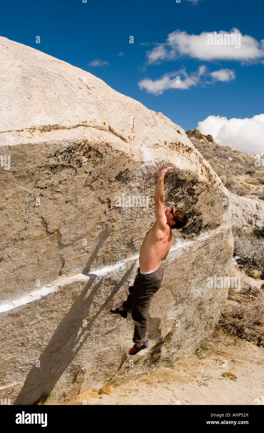 A man leaps for the top of a boulder while climbing near Bishop ...