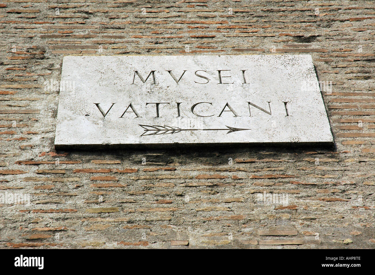 Sign mounted on a brick wall directing tourists to the Vatican Museum ...
