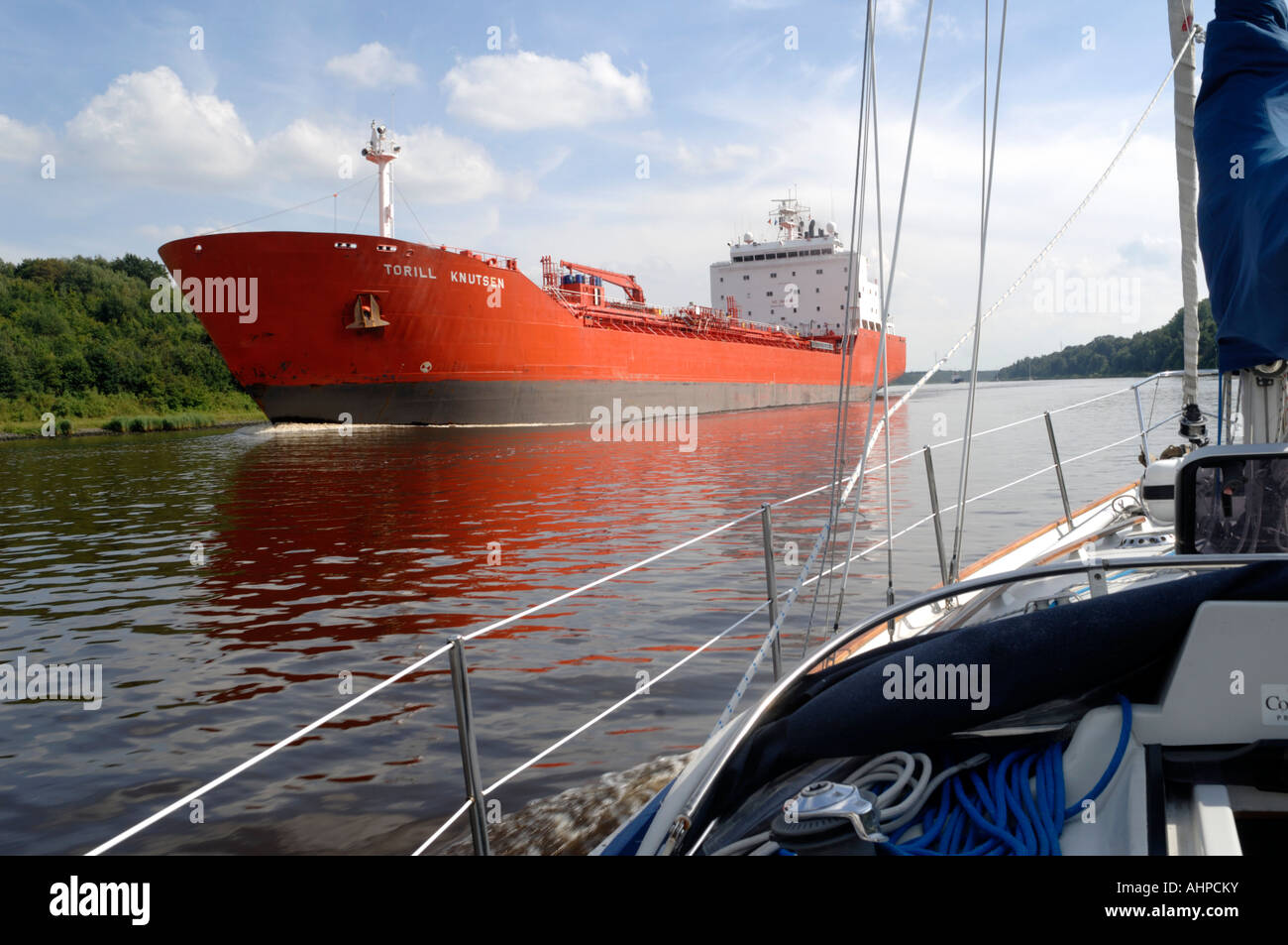 A ship passing a yacht on the Kiel Canal in Schleswig Holstein Germany ...