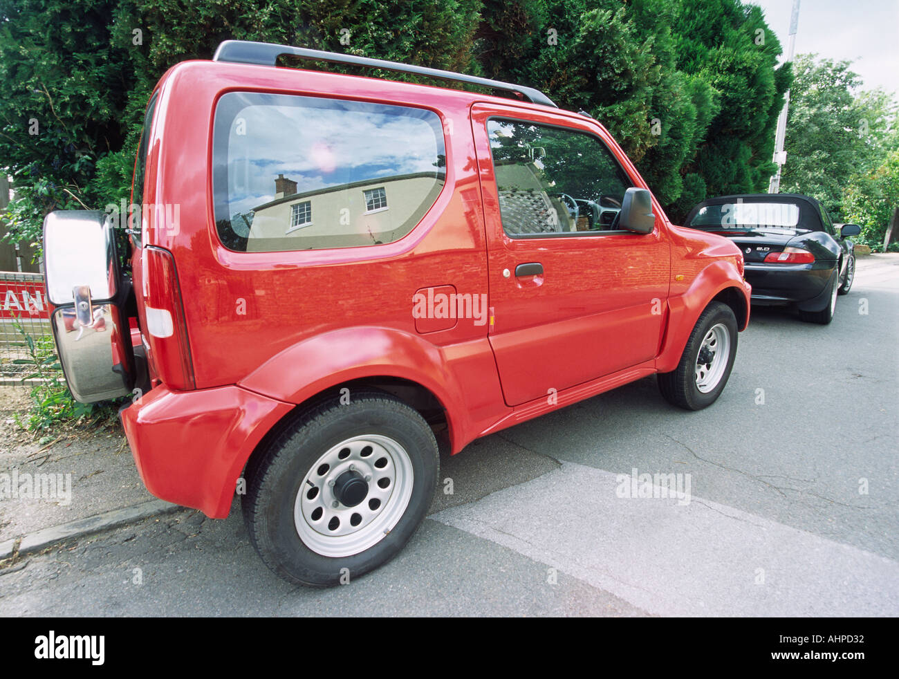 Red Suzuki Jimny Parked by Hedge and Showing Reflection of Cottage ...