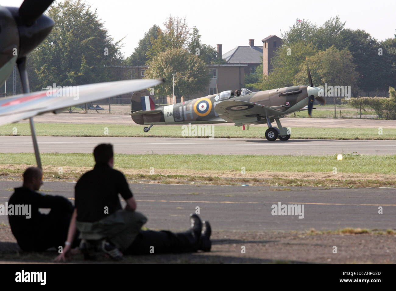 Engineers in the shadow of a spitfire wing watch a Spitfire take off ...