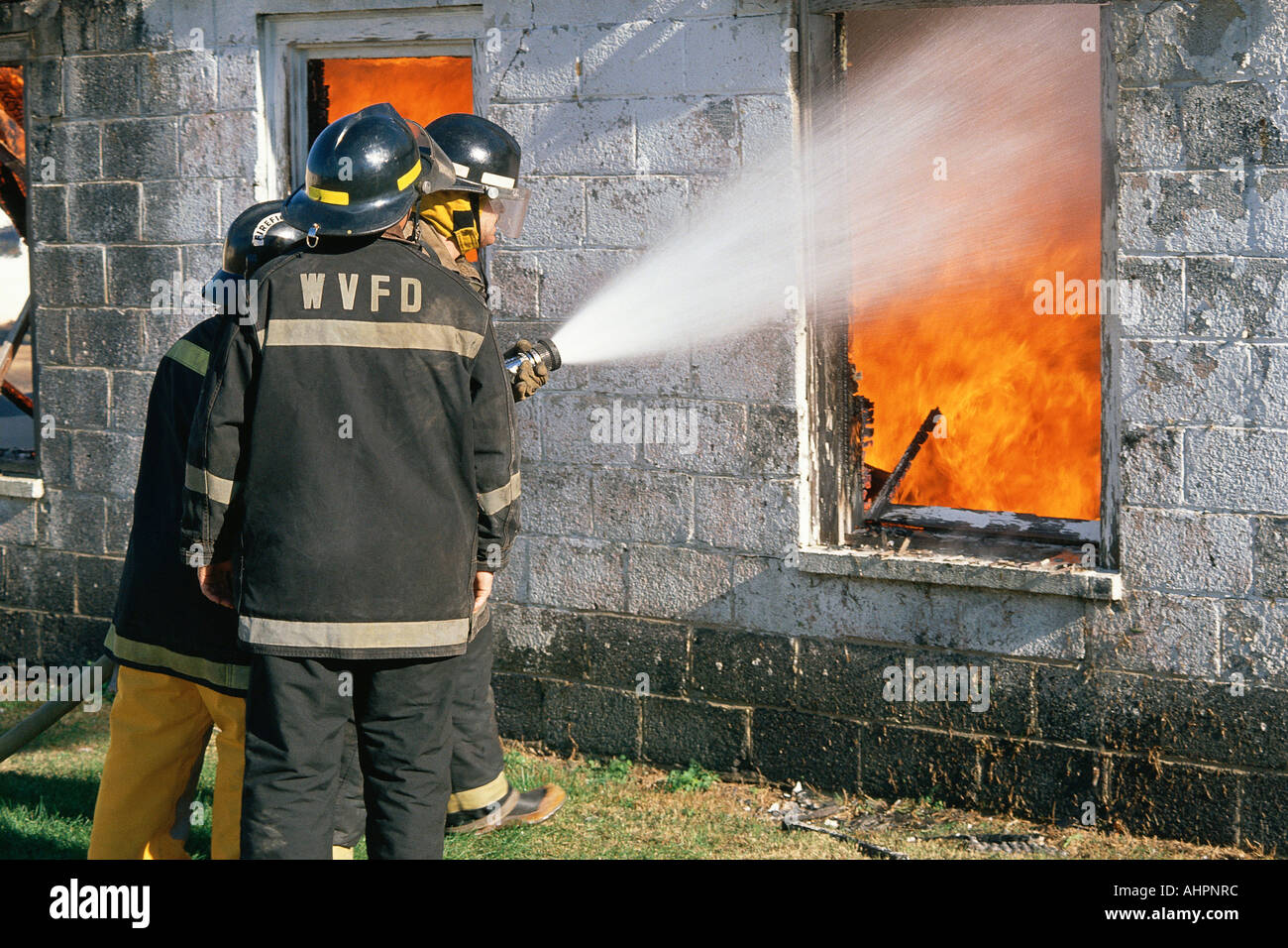 Fireman hosing down a burning building Stock Photo - Alamy