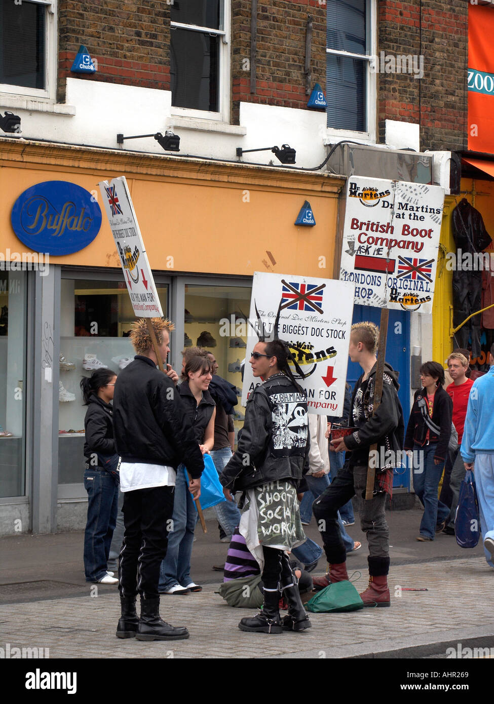 Punk dressed men with sign boards advertising on sidewalk Camden High ...