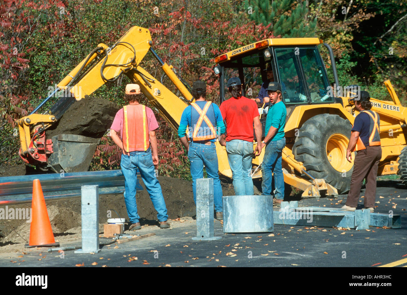 Road repair workers watching backhoe dig a trench New England Stock ...