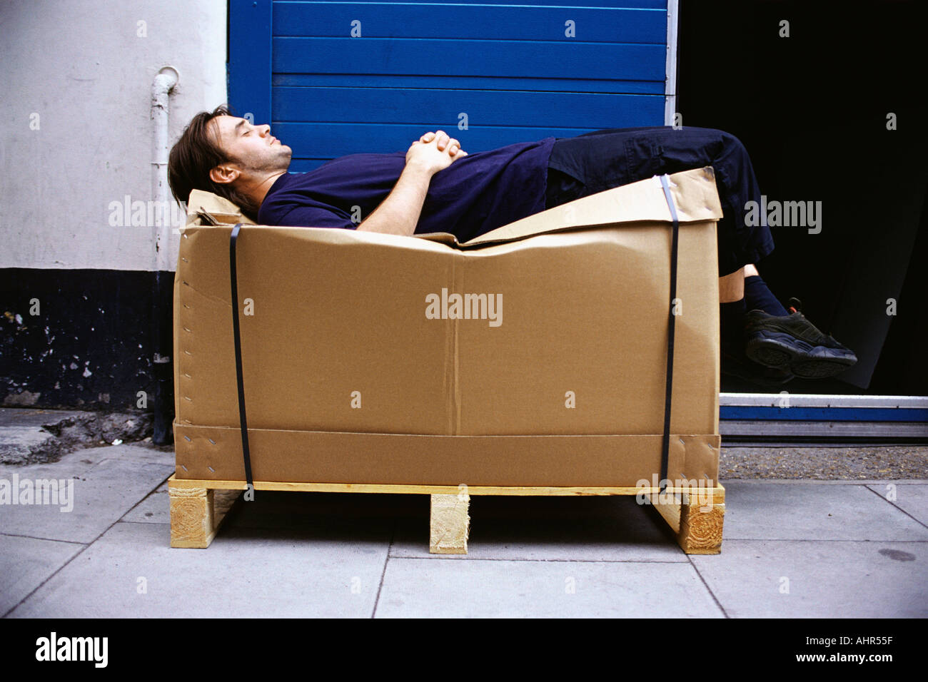 Man resting on cardboard box Stock Photo - Alamy