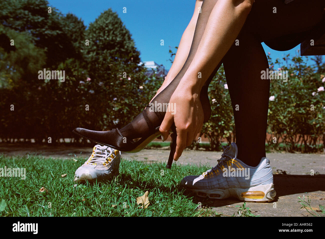 Woman changing shoes in park Stock Photo - Alamy