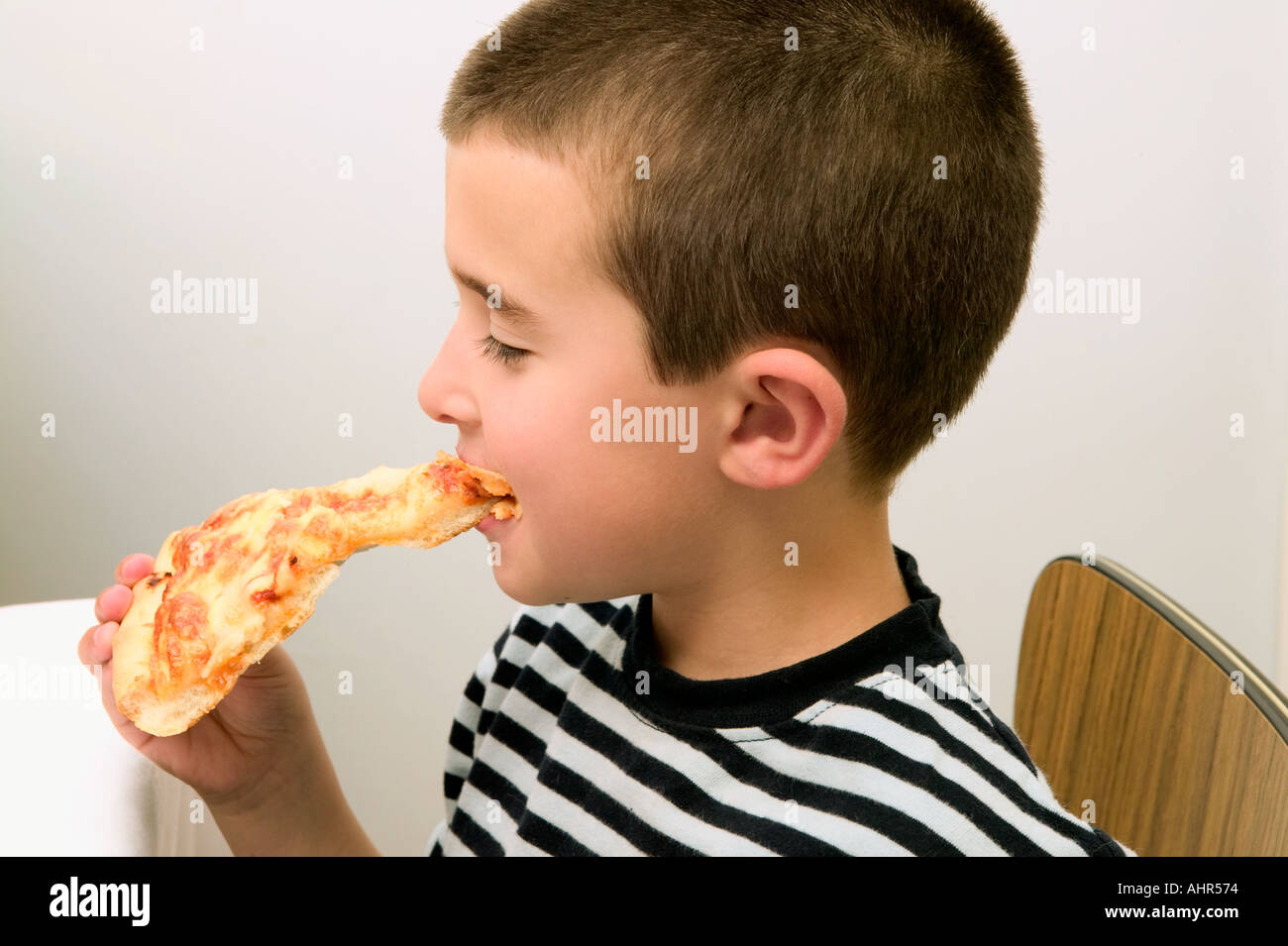 Boy eating a slice of pizza Stock Photo - Alamy