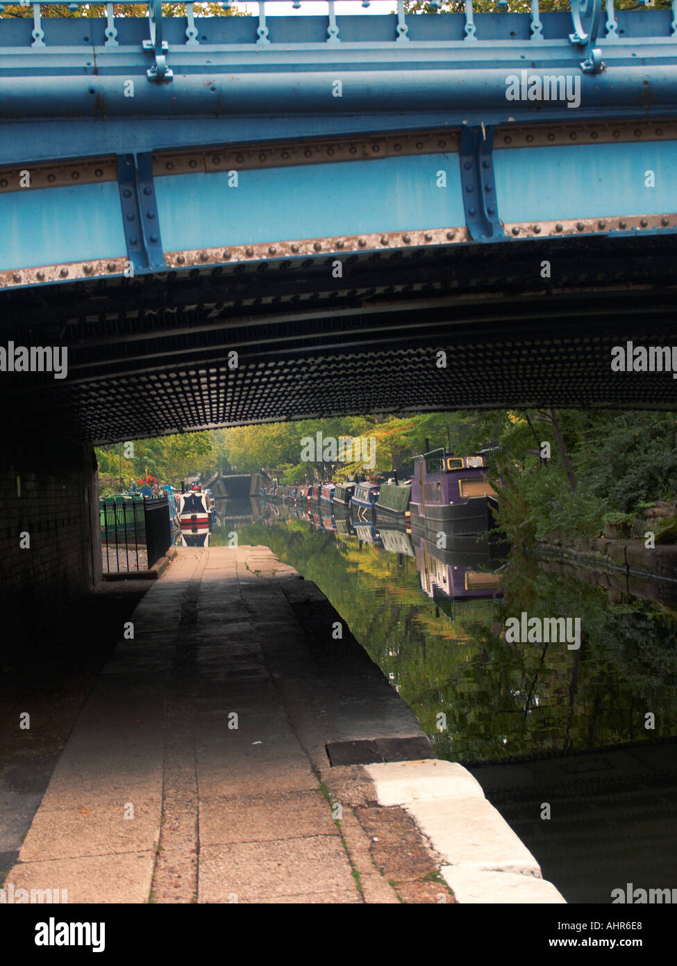 Towpath and walkway under bridge over Regents Canal with houseboats in ...