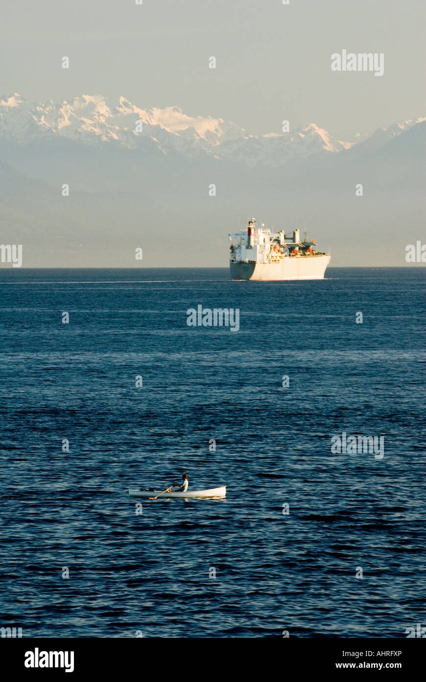 A rower and a cargo ship pass by Washington State s Olympic Mountains ...