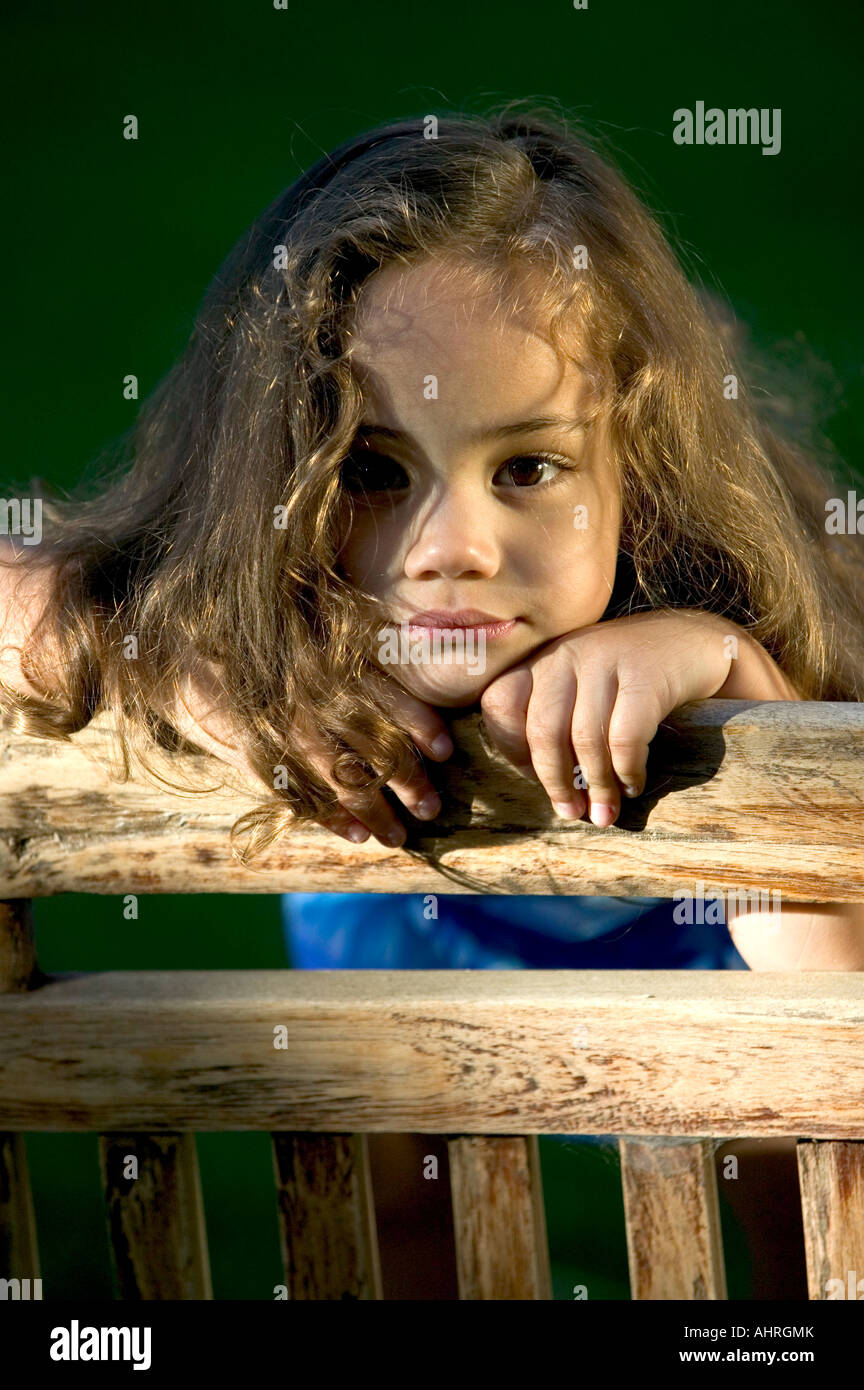 Beautiful little girl leaning on a bench Stock Photo - Alamy