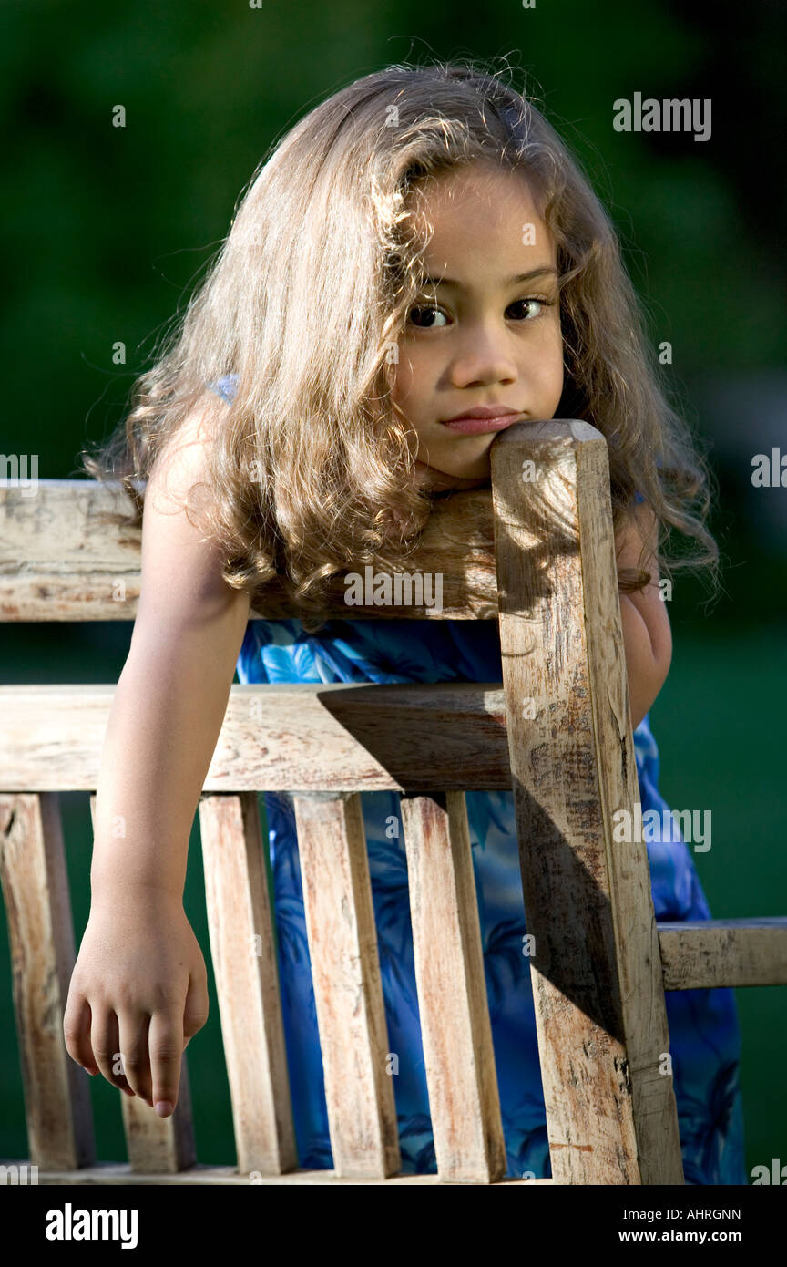 Beautiful little girl leaning on a bench Stock Photo - Alamy