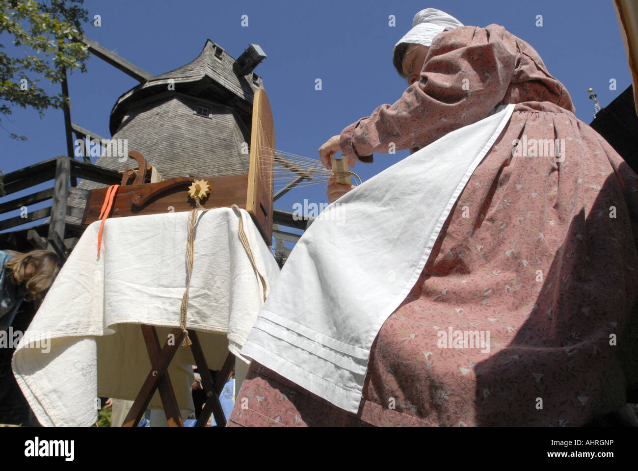 A woman in period dress from the late 1800 s works on a box loom in ...