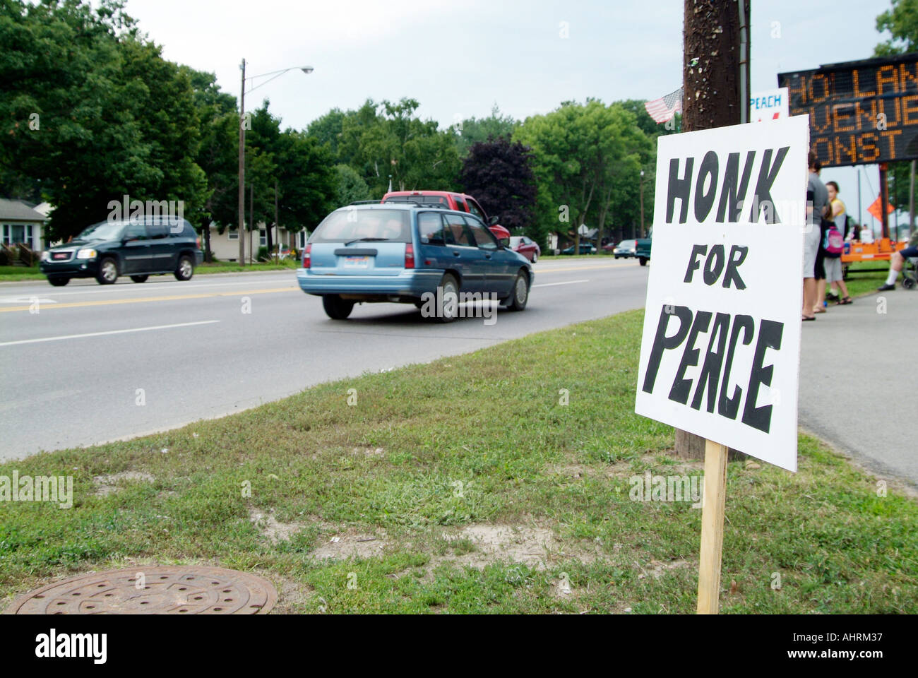 Protesters line a busy city street holding signs to protest war and ...