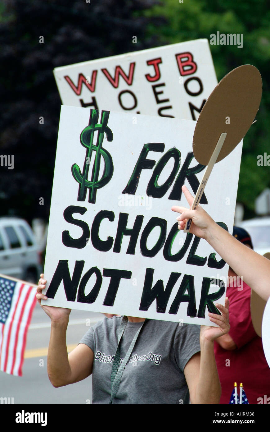 Protesters line a busy city street holding signs to protest war and ...