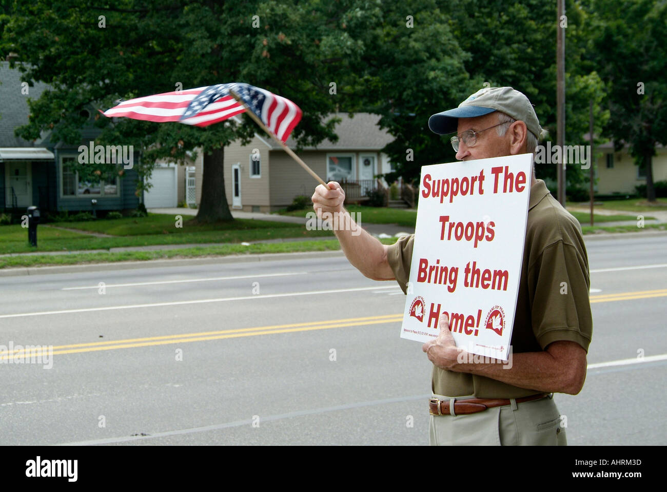 Protesters line a busy city street holding signs to protest war and ...