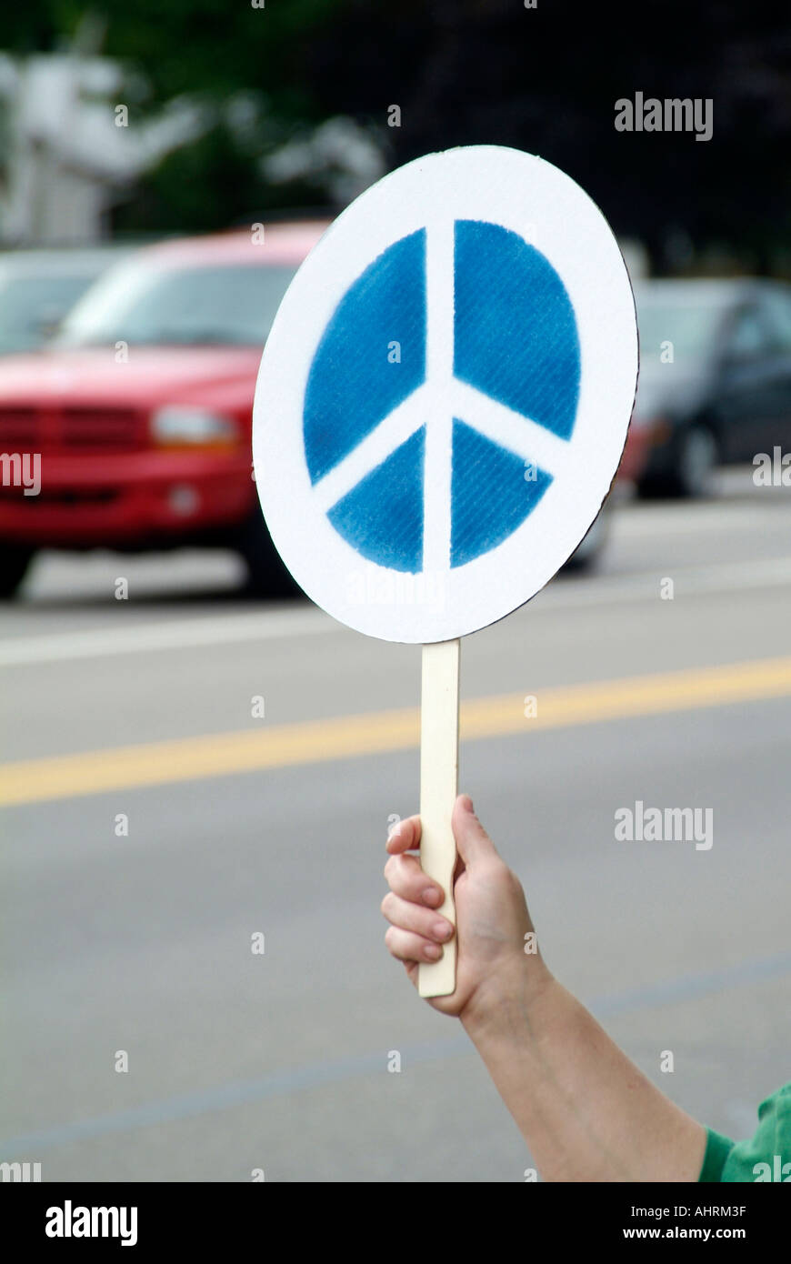 Protesters line a busy city street holding signs to protest war and ...