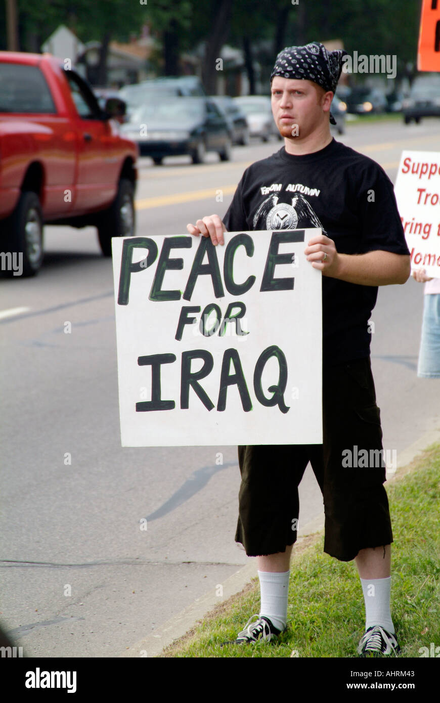 Protesters line a busy city street holding signs to protest war and ...