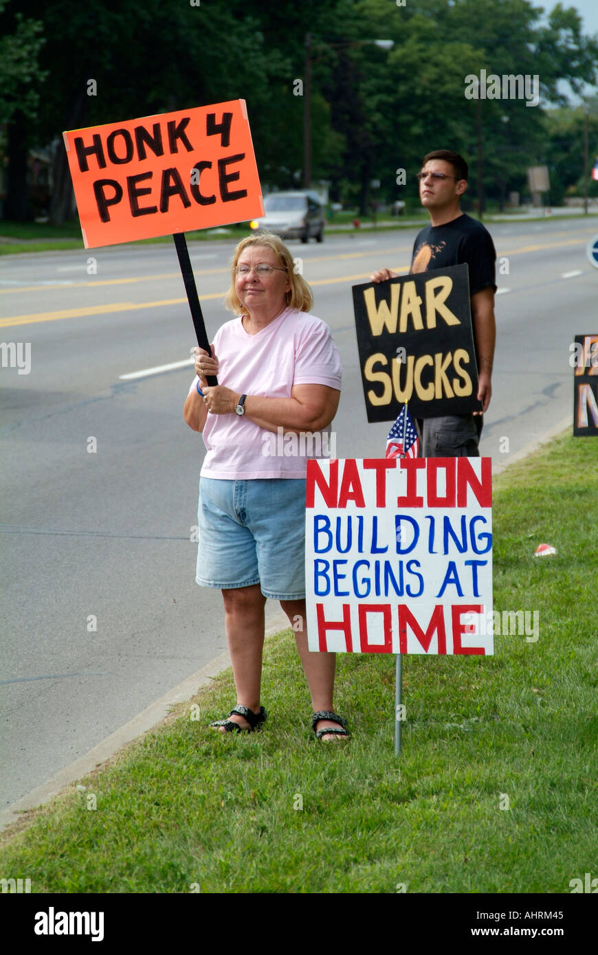 Protesters line a busy city street holding signs to protest war and ...