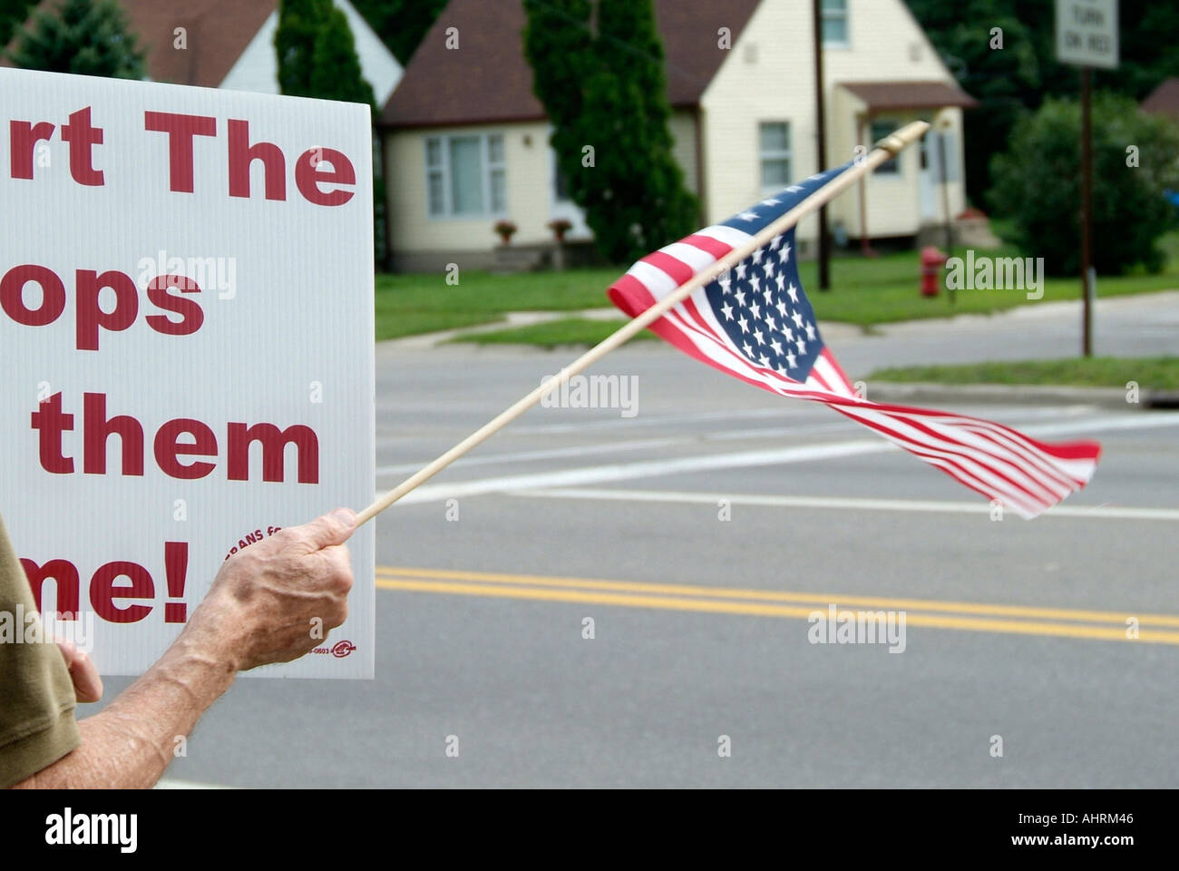 Protesters line a busy city street holding signs to protest war and ...