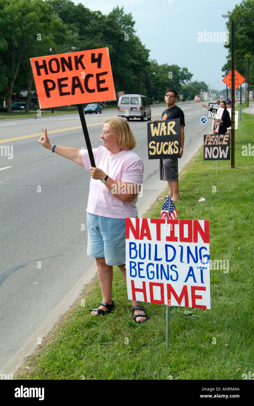 Protesters line a busy city street holding signs to protest war and ...