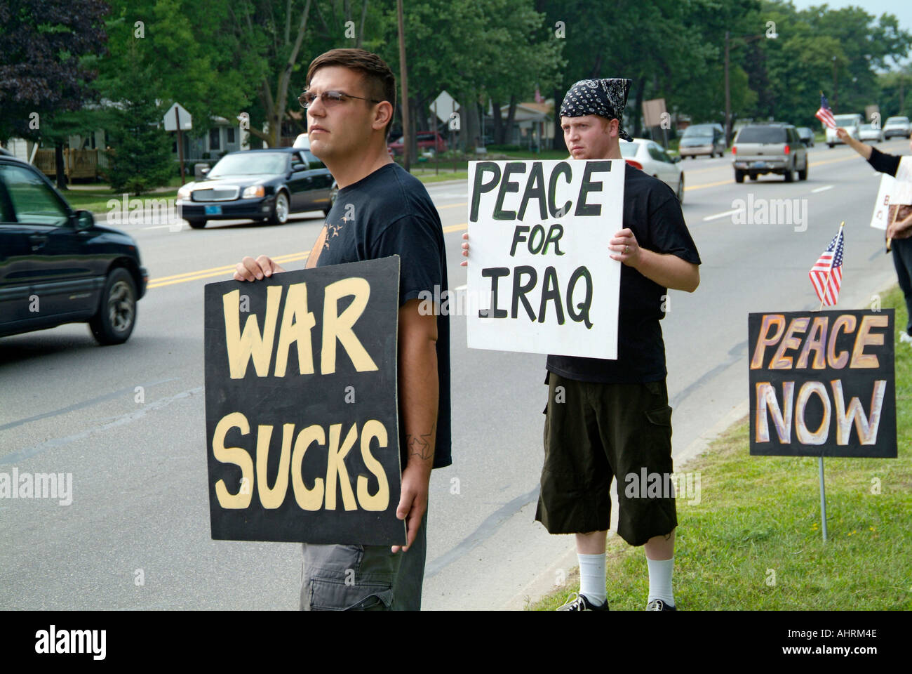 Protesters line a busy city street holding signs to protest war and ...