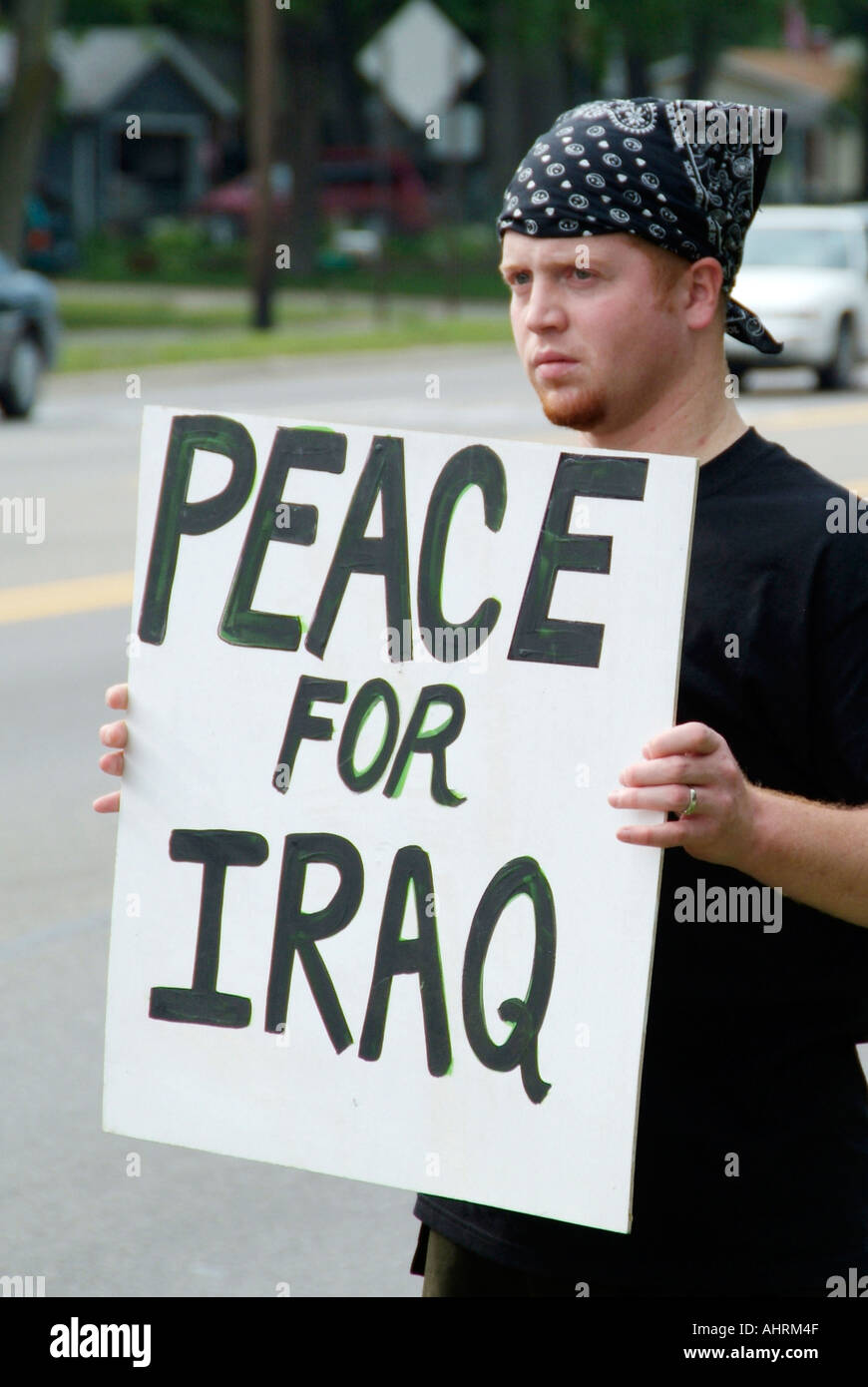 Protesters line a busy city street holding signs to protest war and ...