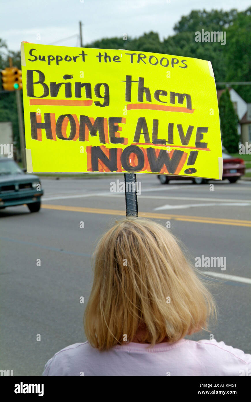 Protesters line a busy city street holding signs to protest war and ...