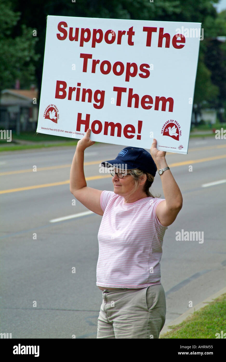 Protesters line a busy city street holding signs to protest war and ...