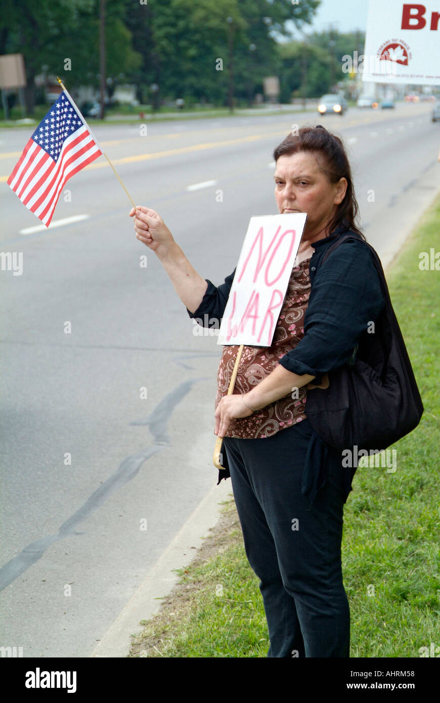 Protesters line a busy city street holding signs to protest war and ...