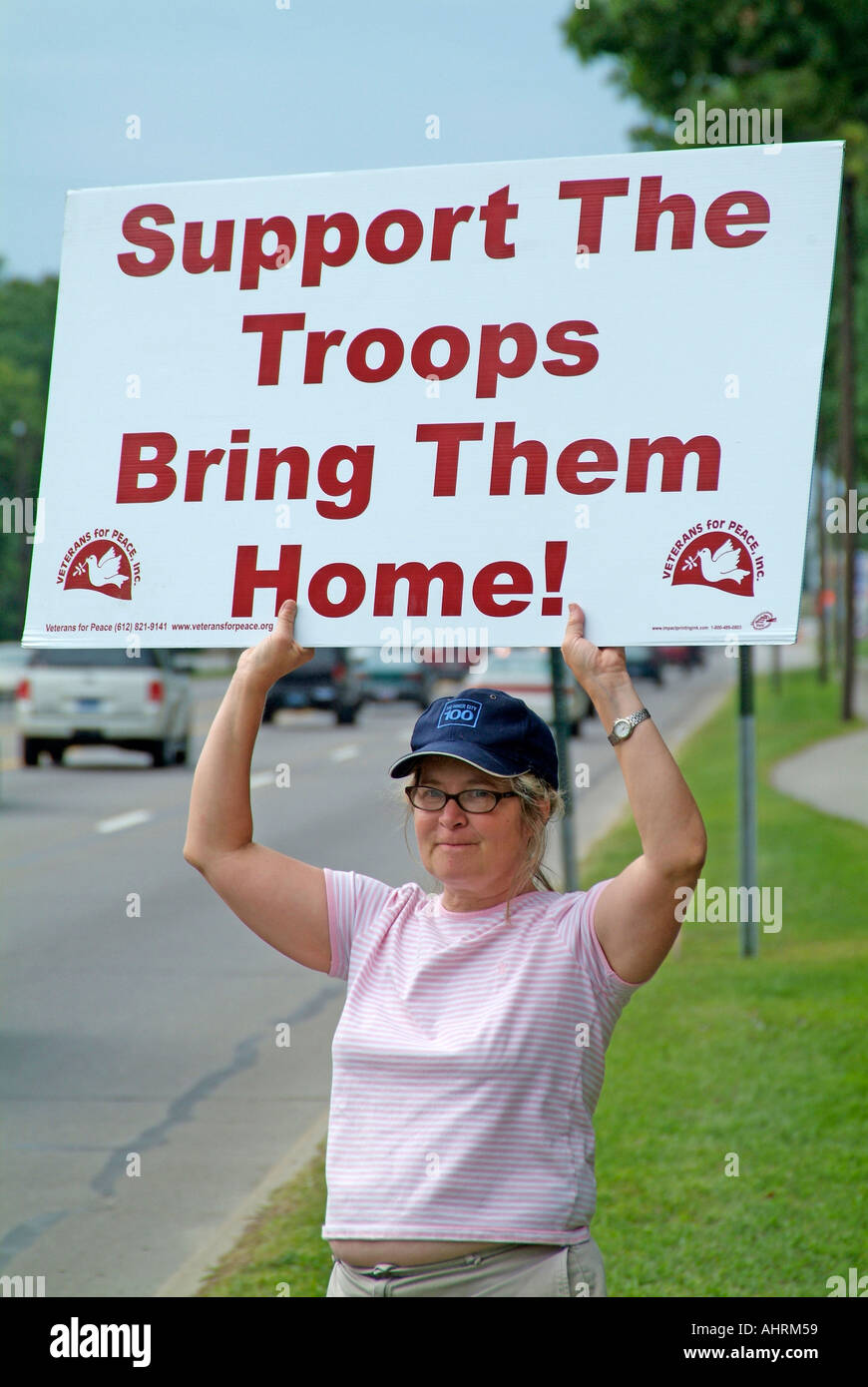 Protesters line a busy city street holding signs to protest war and ...