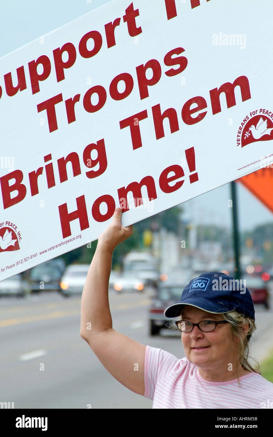 Protesters line a busy city street holding signs to protest war and ...