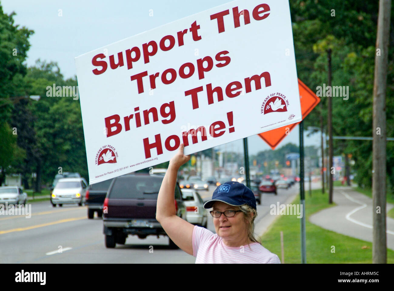 Protesters line a busy city street holding signs to protest war and ...
