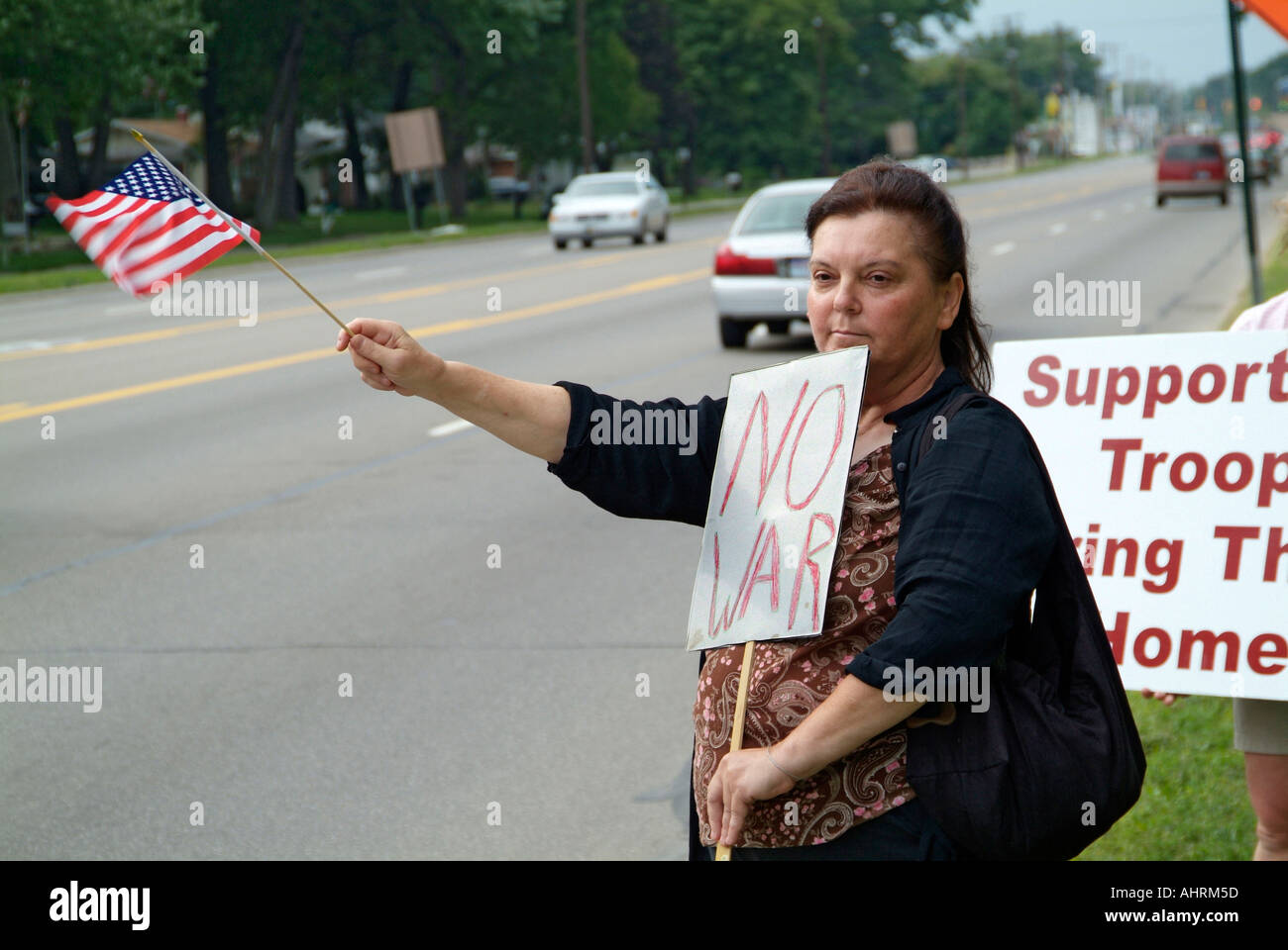 Protesters line a busy city street holding signs to protest war and ...