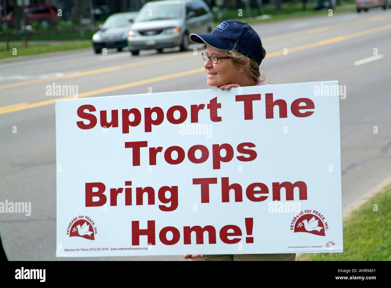 Protesters line a busy city street holding signs to protest war and ...