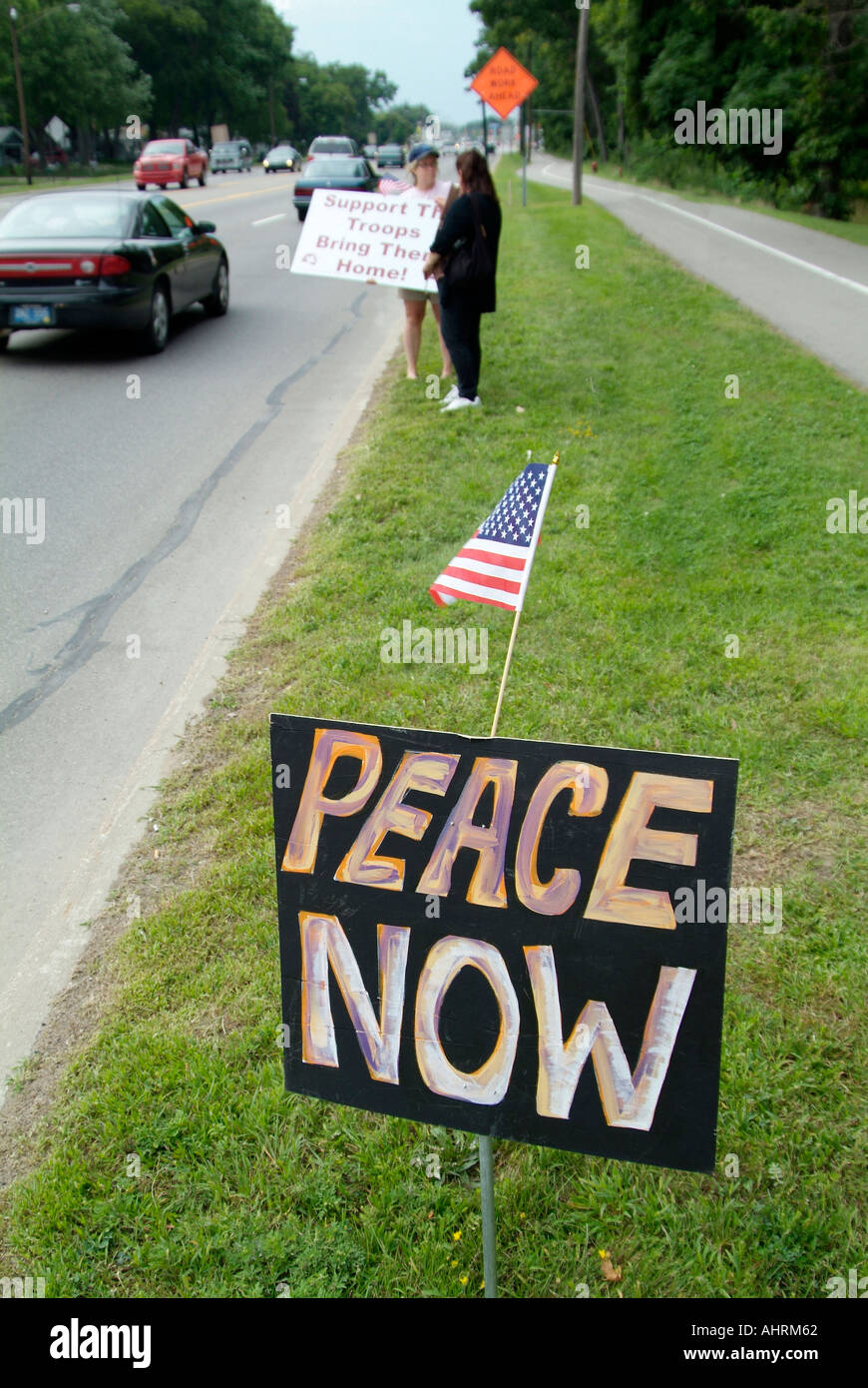 Protesters line a busy city street holding signs to protest war and ...