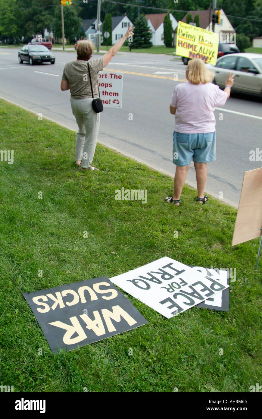 Protesters line a busy city street holding signs to protest war and ...