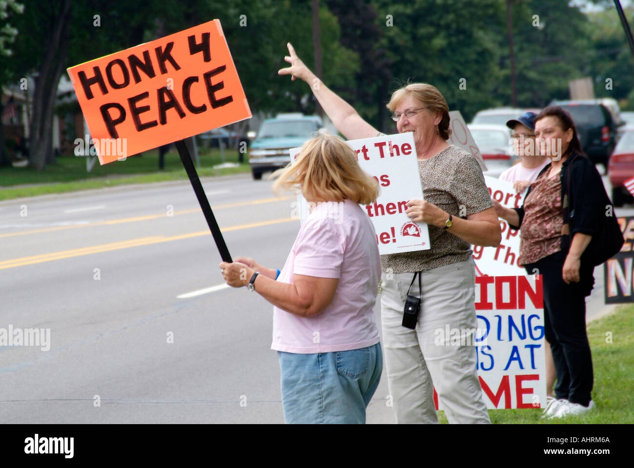 Protesters line a busy city street holding signs to protest war and ...